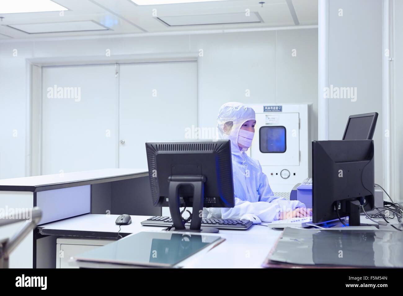 Female factory worker using computer in flexible electronics factory ...