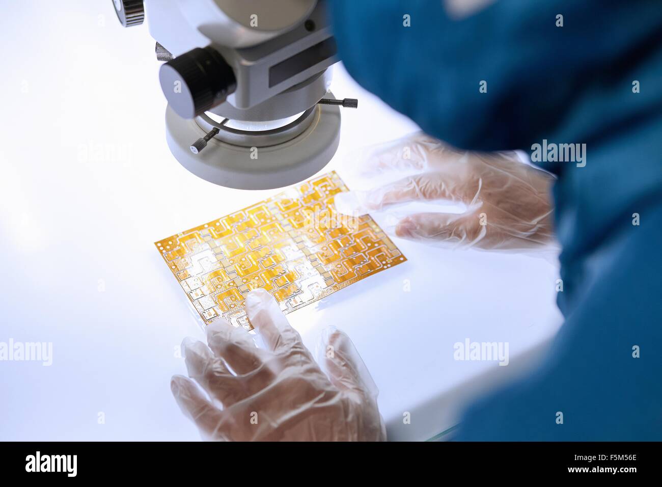 Over the shoulder view of female worker using microscope to examine ...