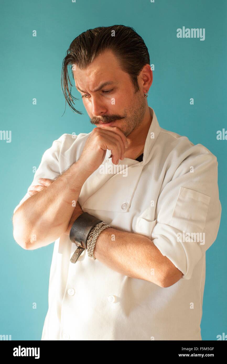 Studio portrait of mid adult male chef with hand on chin Stock Photo ...