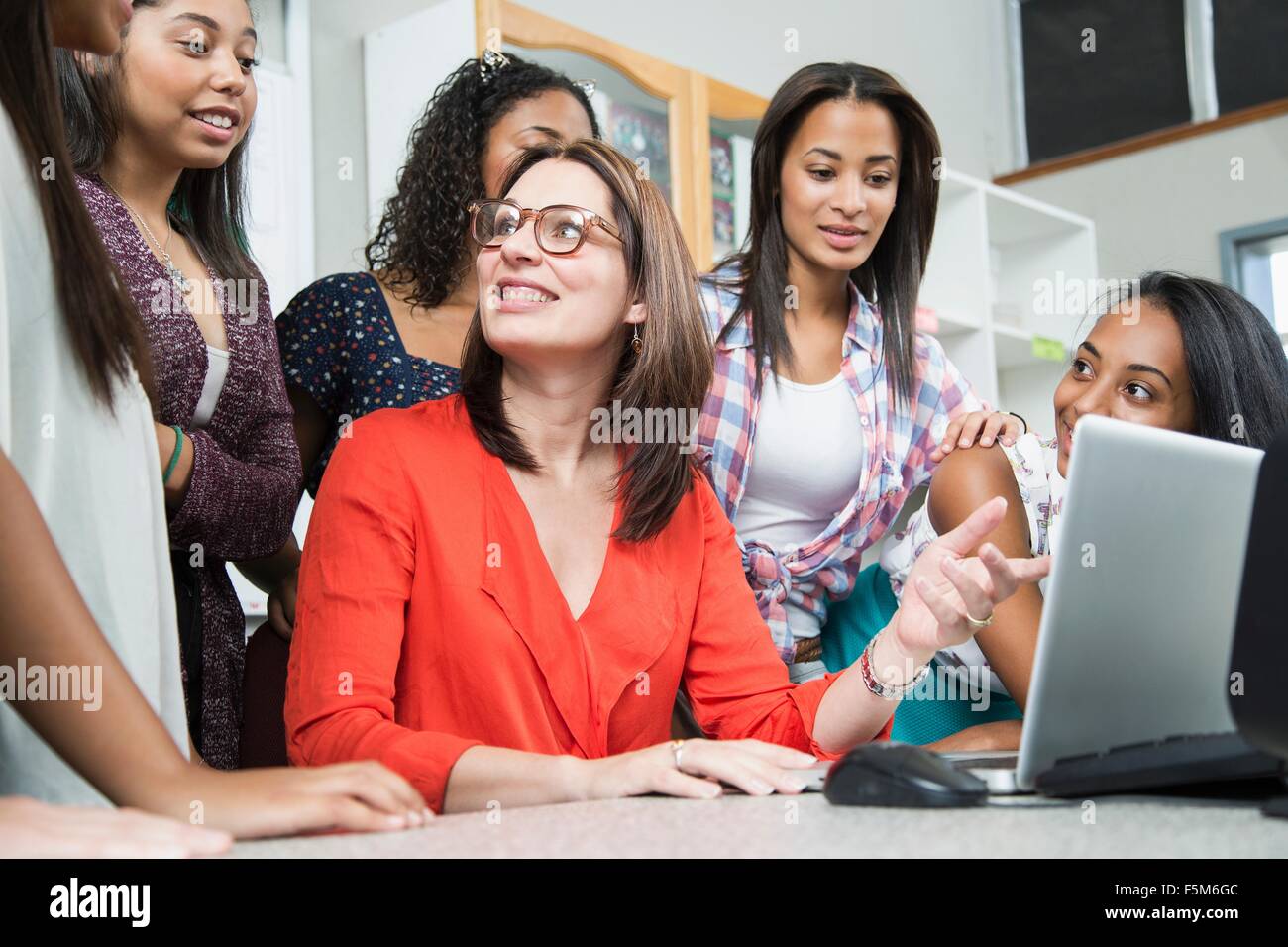 Female teacher explaining on laptop to high school students Stock Photo ...