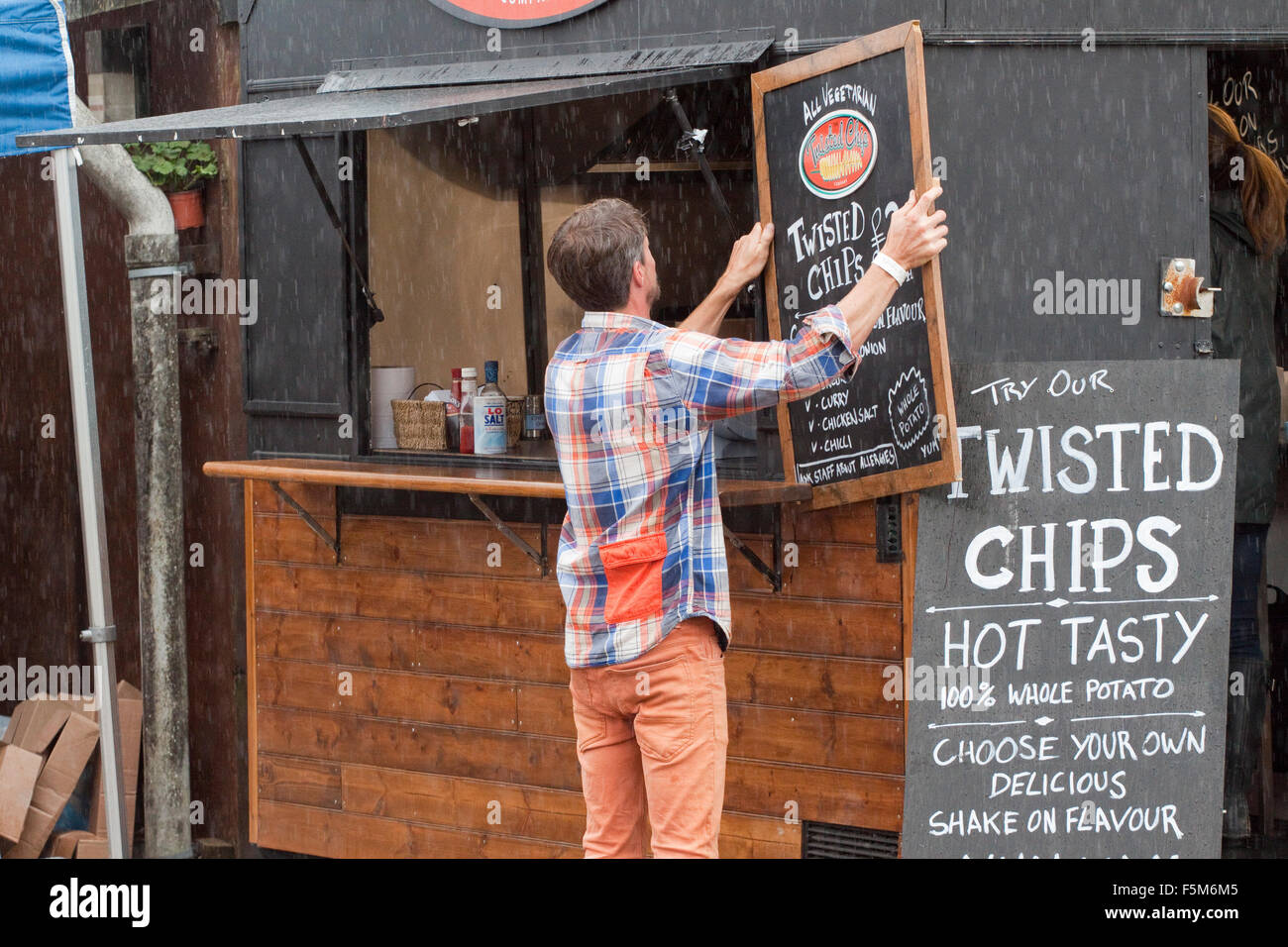 Man putting up/taking down a sign on an outdoor food stall Stock Photo ...