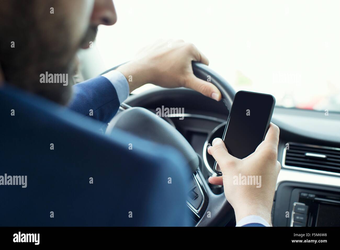 Young businessman reading smartphone text in car Stock Photo - Alamy