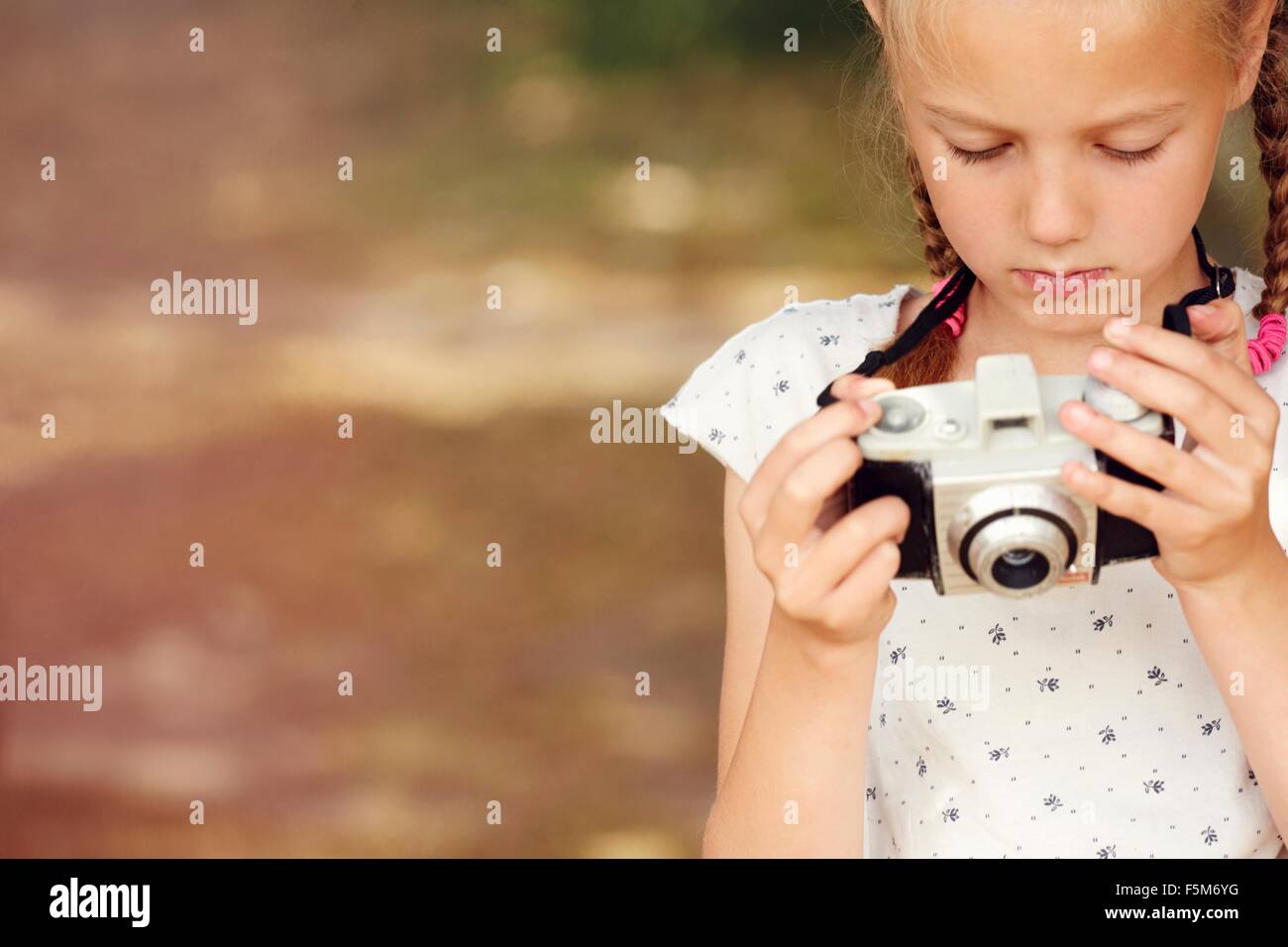 Cropped view of girl holding film camera looking down Stock Photo - Alamy
