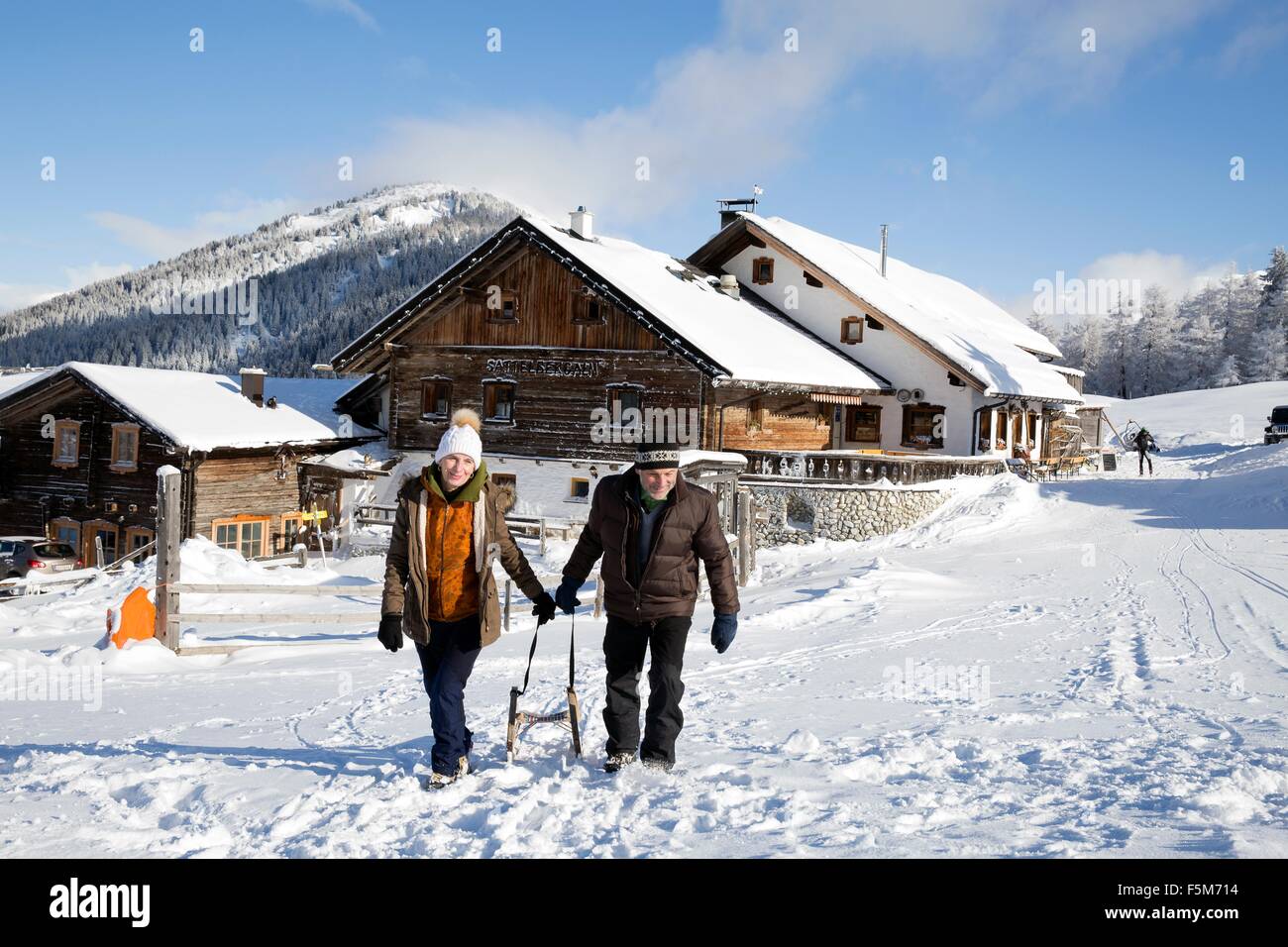 Senior couple pulling sledge and log cabin, Sattelbergalm, Tyrol ...
