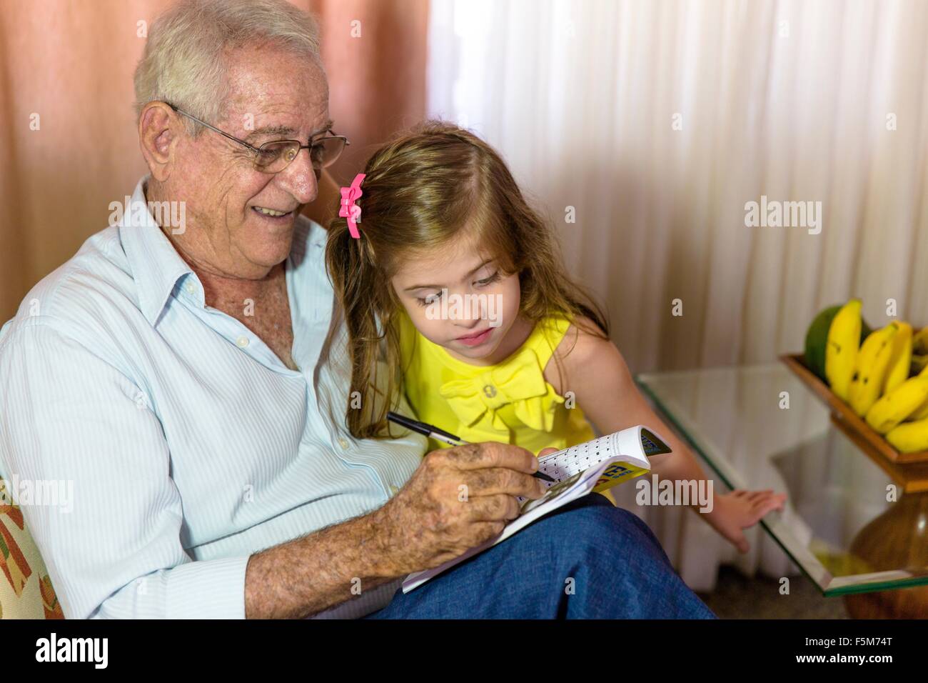 Girl looking at grandfather writing in notebook Stock Photo - Alamy