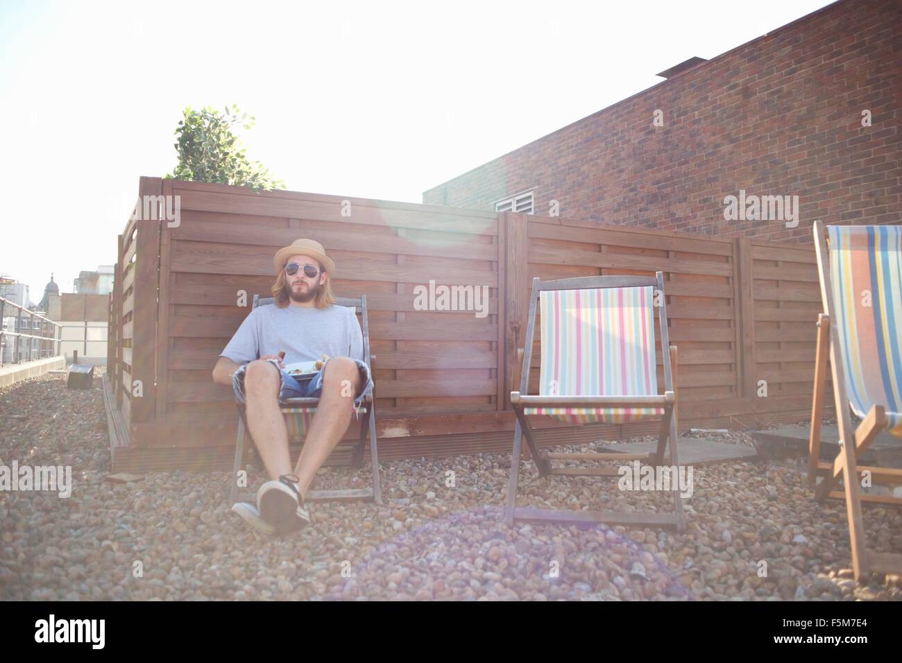 Young man alone on deckchair at rooftop party Stock Photo - Alamy