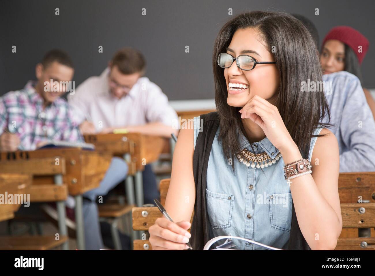 Female student, sitting at desk in classroom, smiling Stock Photo - Alamy
