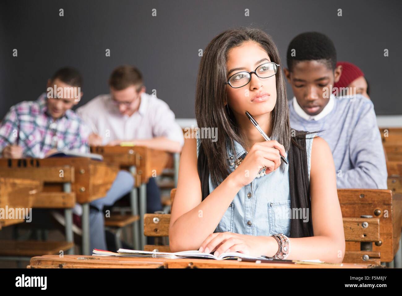 Female student, sitting at desk in classroom, thinking Stock Photo - Alamy