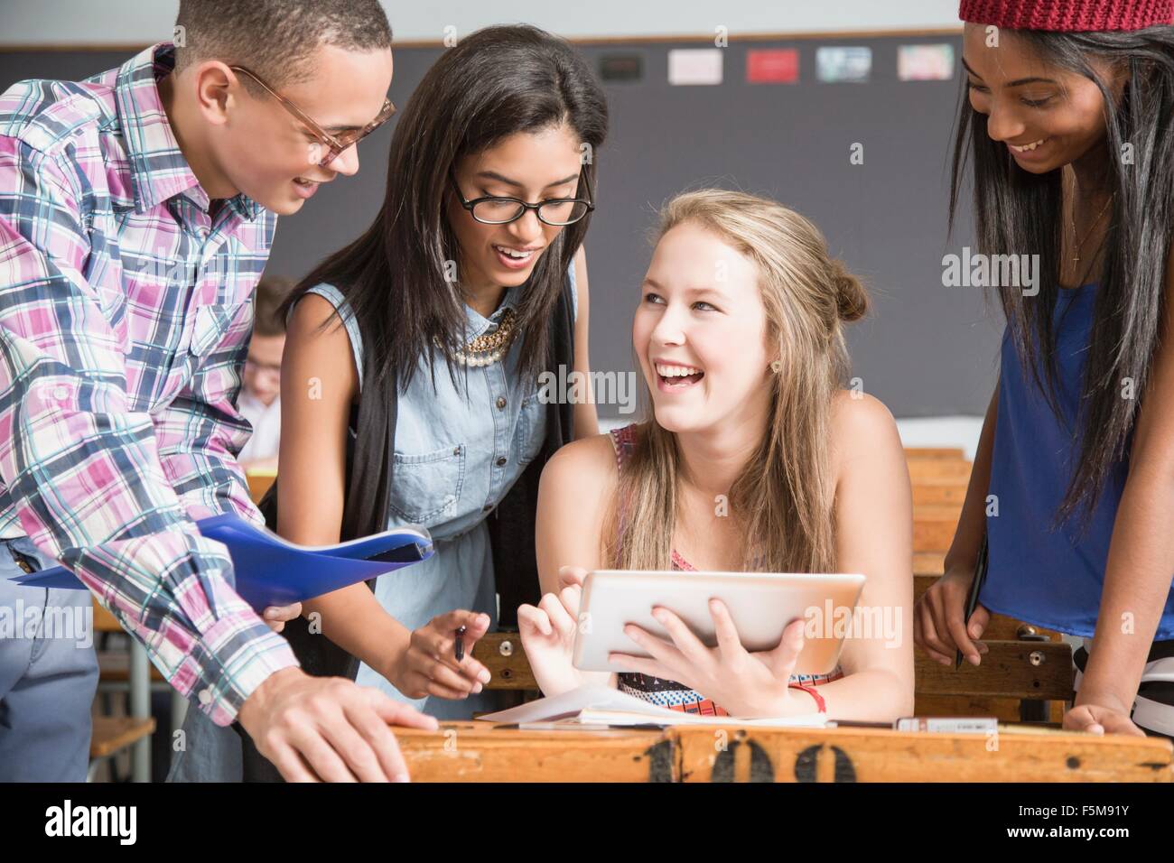 Group of students in classroom, looking at digital tablet Stock Photo ...