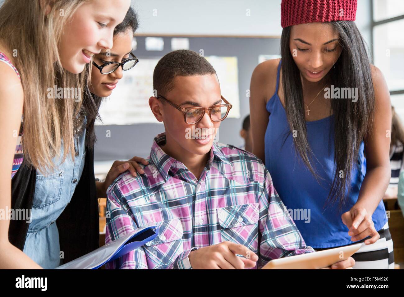 Group of students in classroom, looking at digital tablet Stock Photo ...