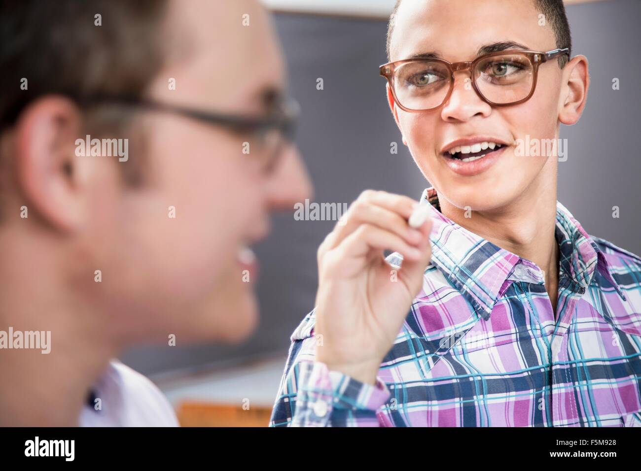 Two male students talking in classroom Stock Photo - Alamy