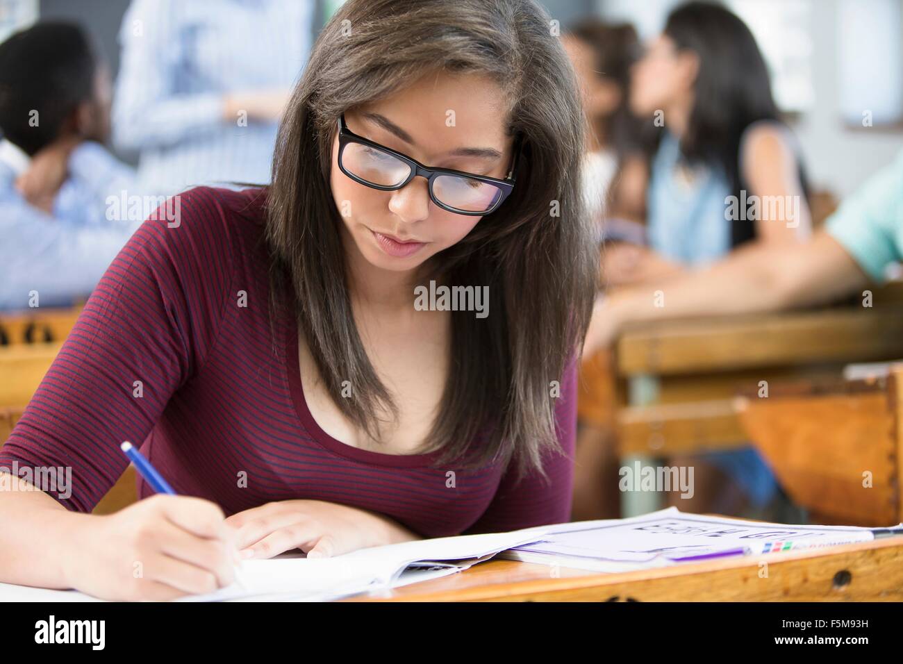 Female student, sitting at desk in classroom, writing Stock Photo - Alamy