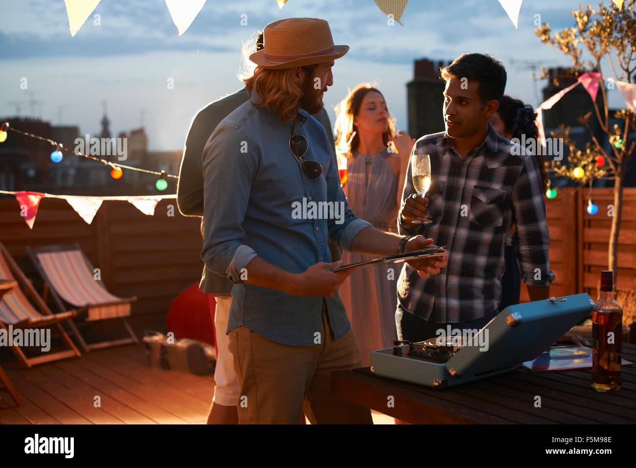 Man putting on music at early evening party Stock Photo - Alamy