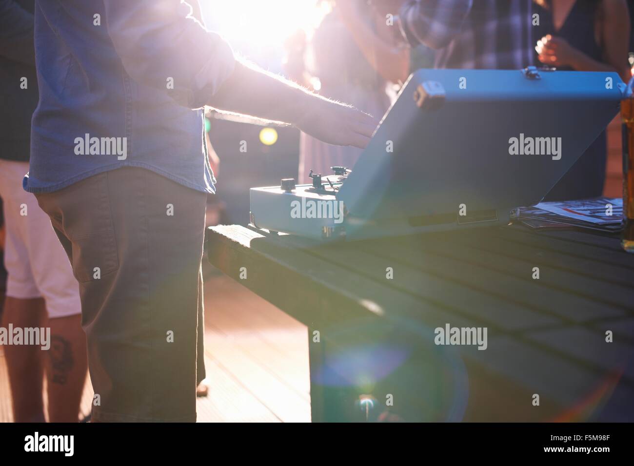 Man putting on music at early evening party Stock Photo - Alamy