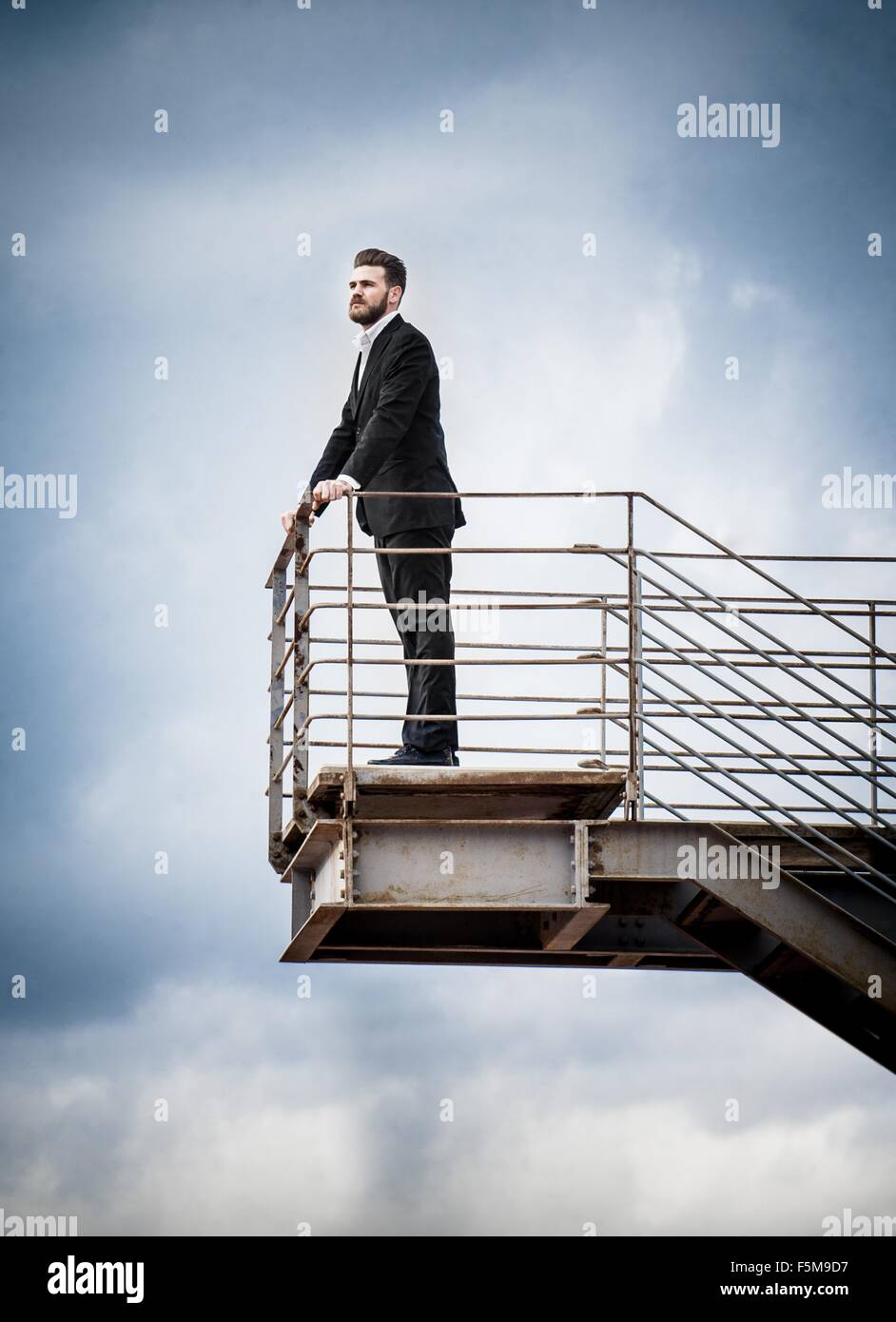 Low angle side view of mid adult man on stairs wearing suit looking ...