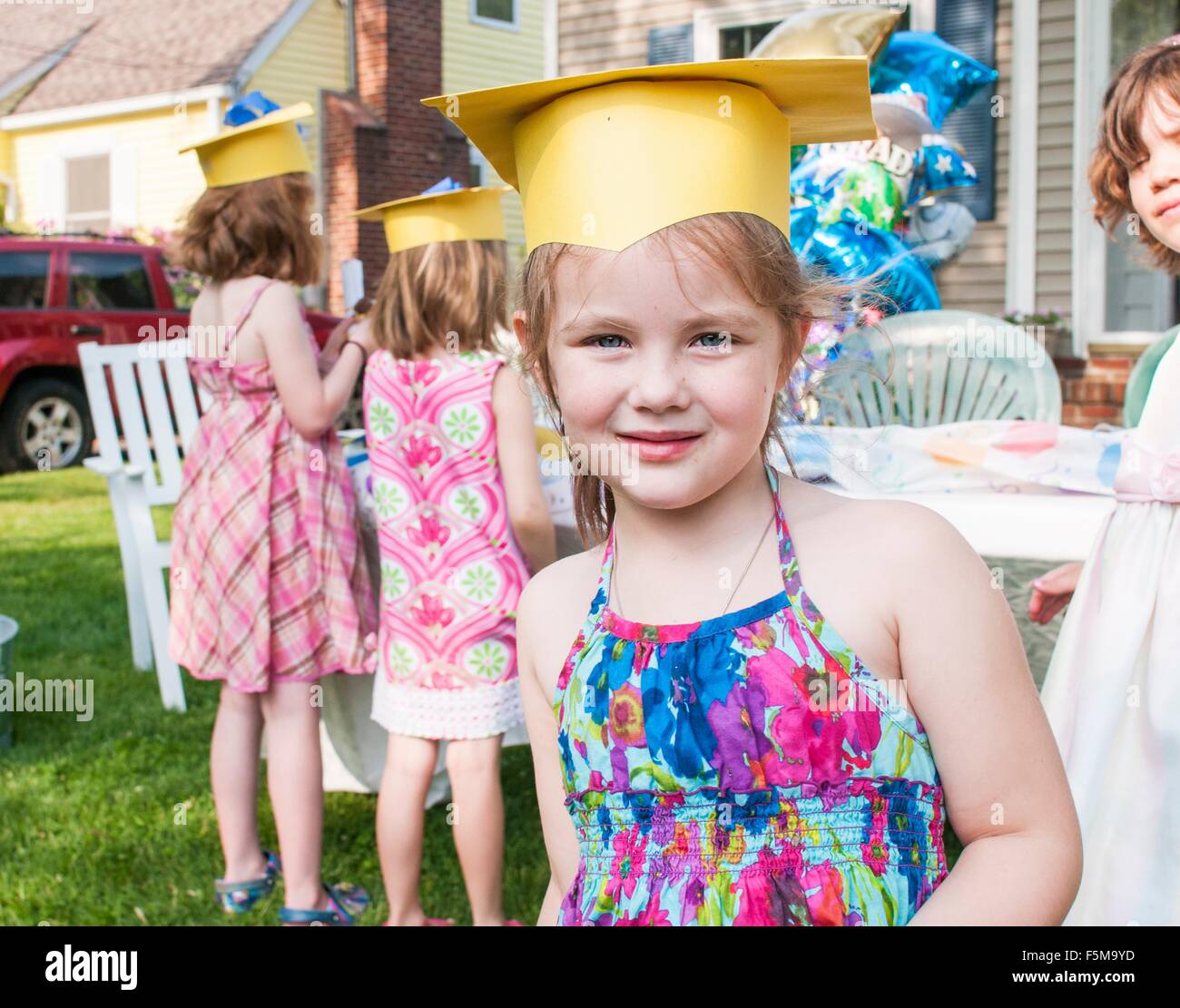 Portrait of young girl at kindergarten graduation, wearing paper mortar ...