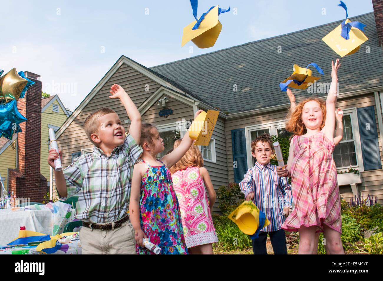 Group of children at kindergarten graduation, throwing paper mortar ...