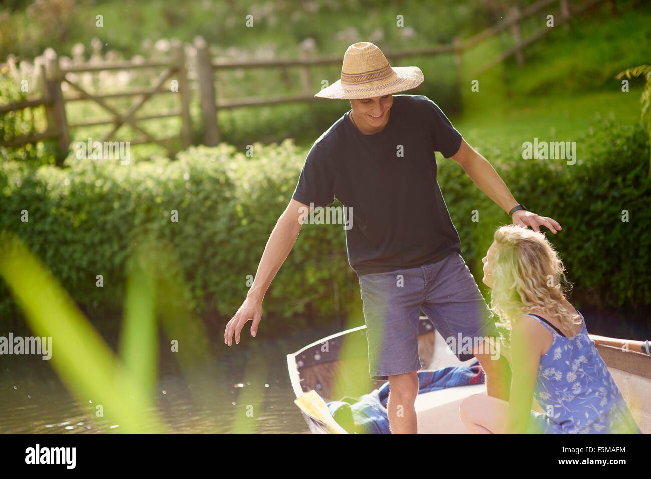 Young man with girlfriend standing in rowing boat on river Stock Photo ...