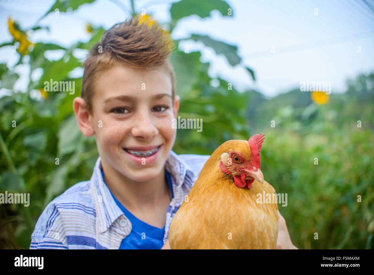 Portrait of boy in field holding hen Stock Photo - Alamy