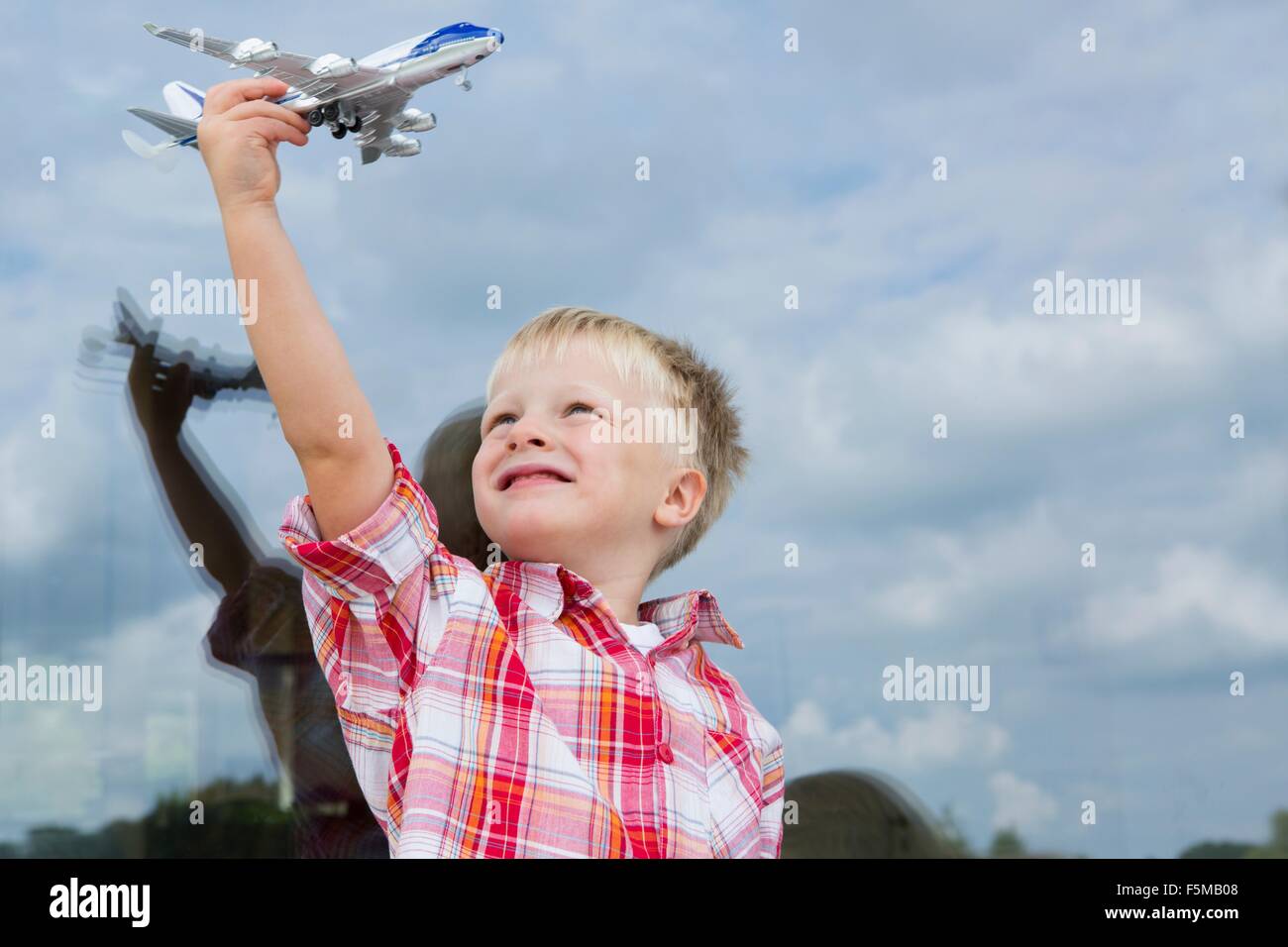 Boy holding up toy airplane in front of house window Stock Photo - Alamy