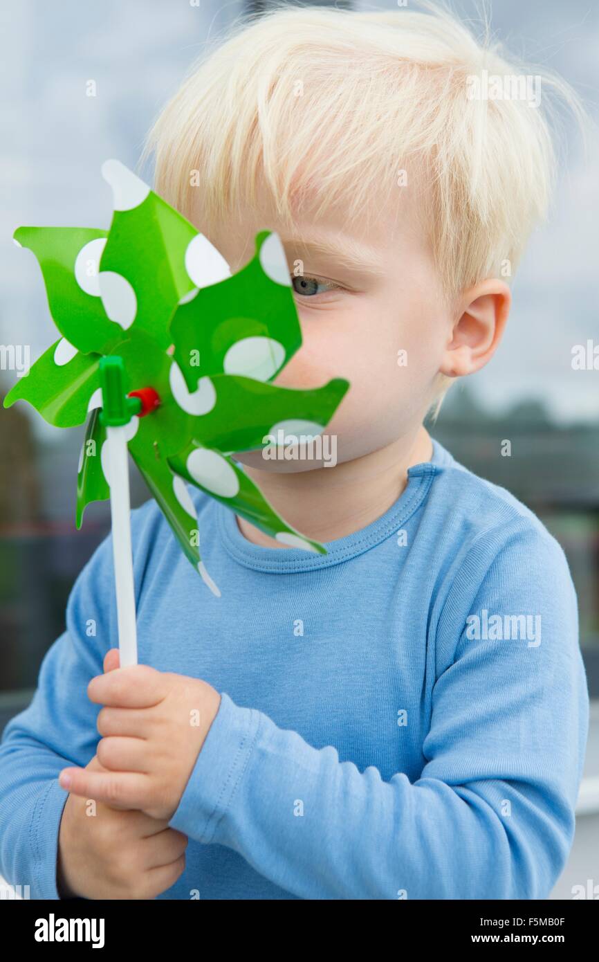 Male toddler blowing pinwheel in front of his face on patio Stock Photo ...