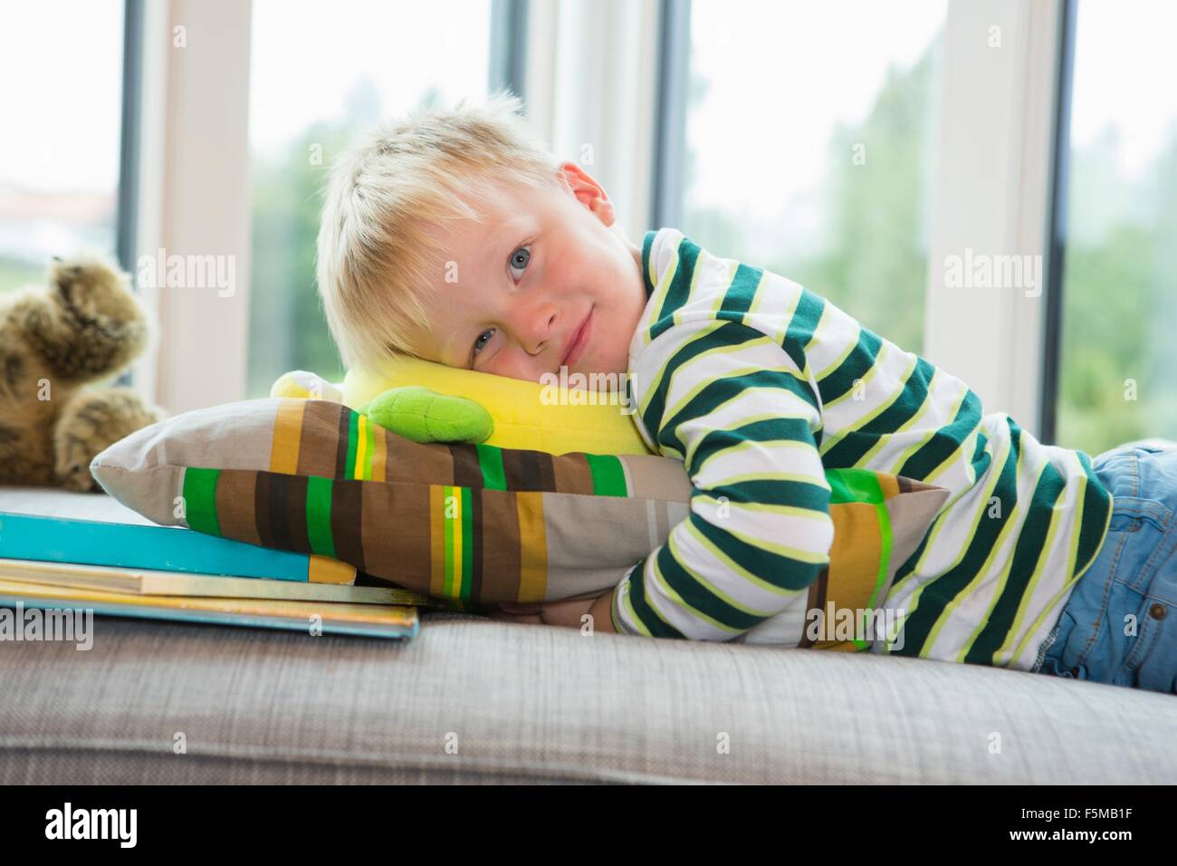 Portrait of tired boy lying on sofa Stock Photo - Alamy