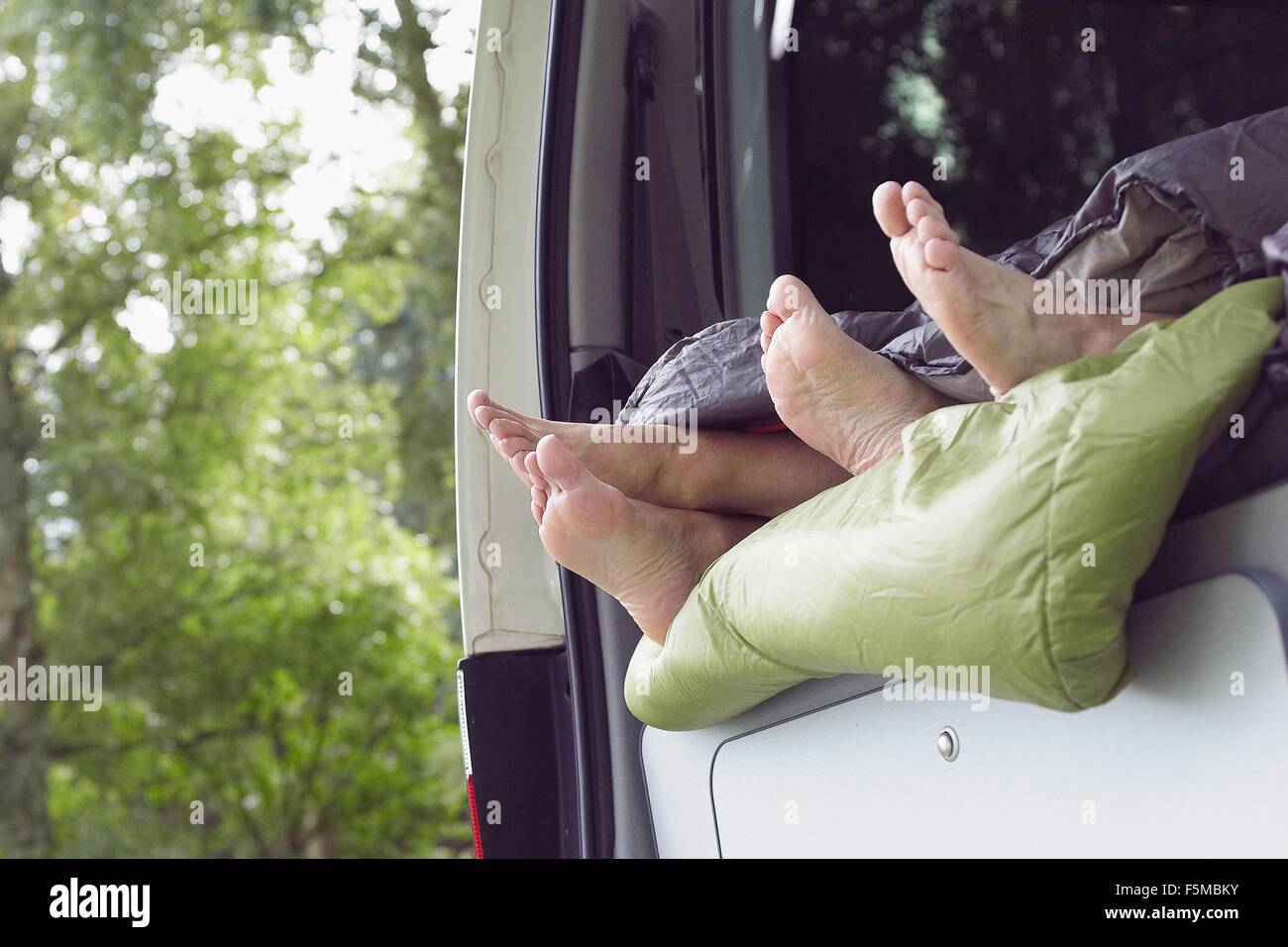 Couple lying inside open camper van, focus on feet Stock Photo - Alamy