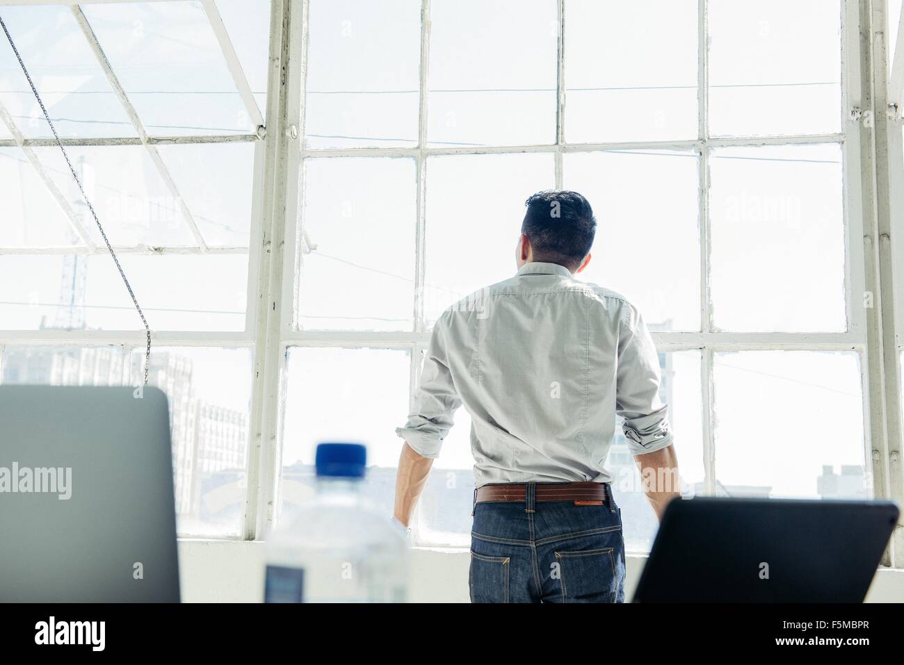 Businessman looking out of office window Stock Photo - Alamy