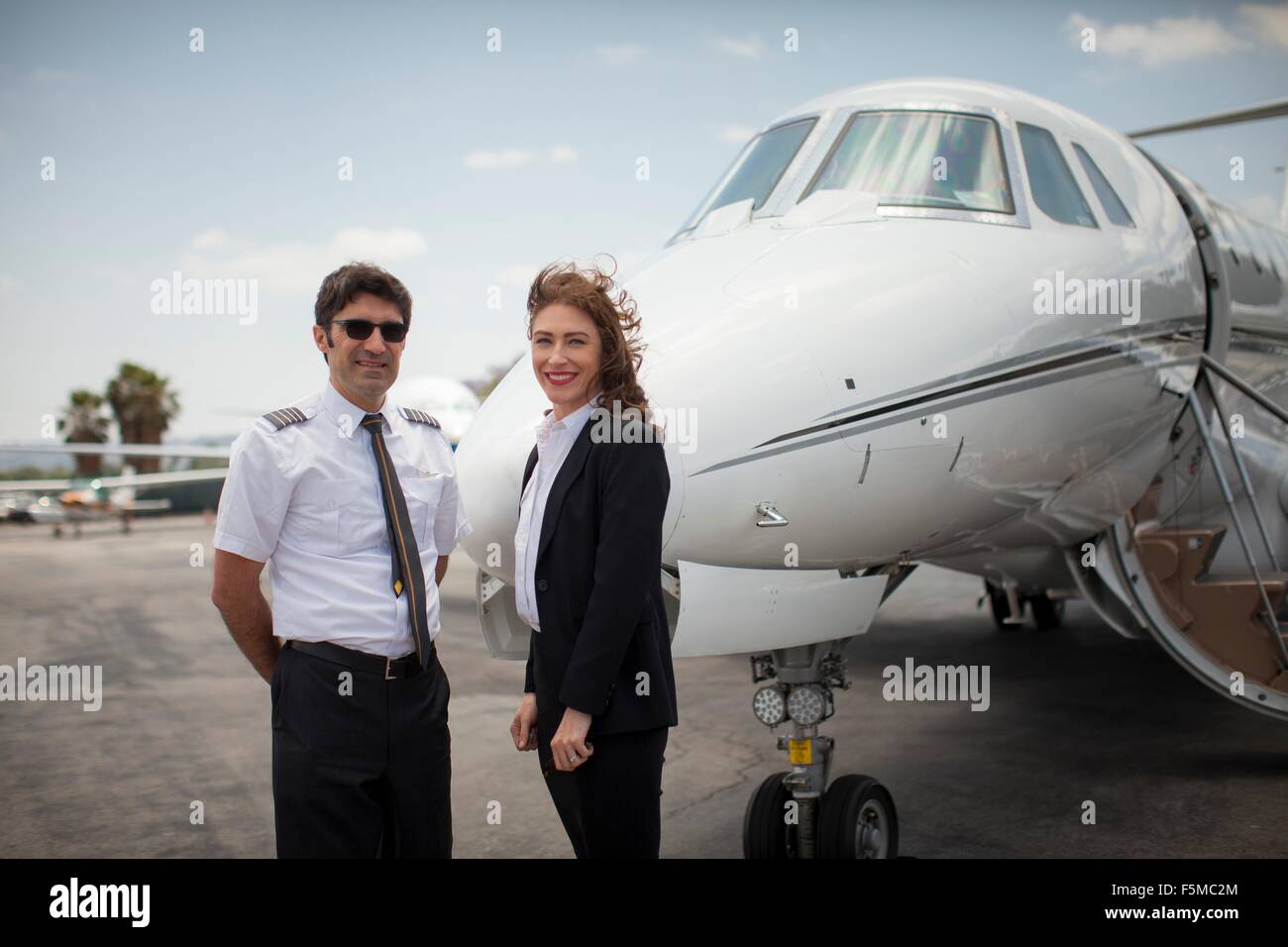 Portrait of female businesswoman and pilot of private jet at airport ...
