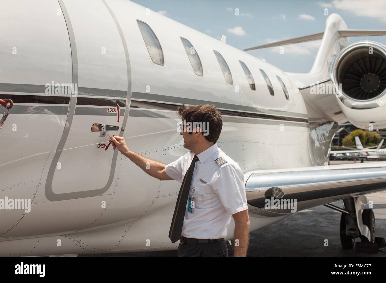 Male private jet pilot locking plane door at airport Stock Photo - Alamy