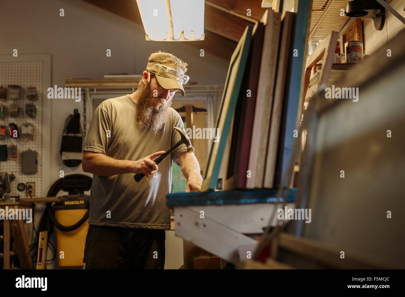 Wood artist working in workshop, using hammer Stock Photo - Alamy