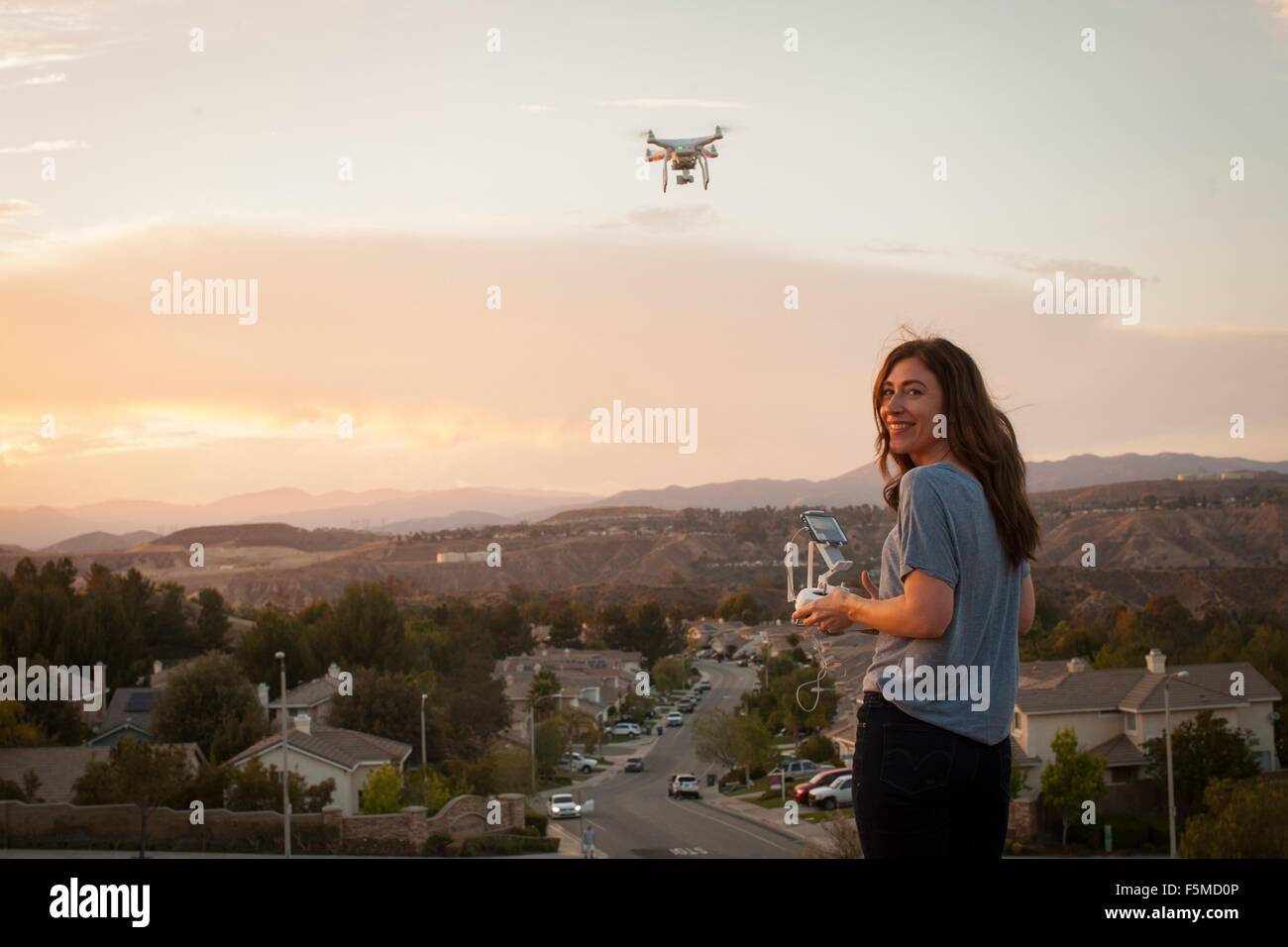 Female commercial operator flying drone above housing development ...