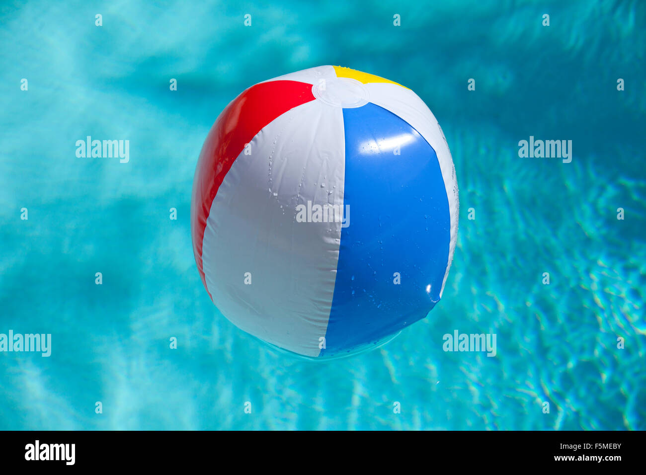 A colourful primary colour beach ball floating on a swimming pool Stock ...