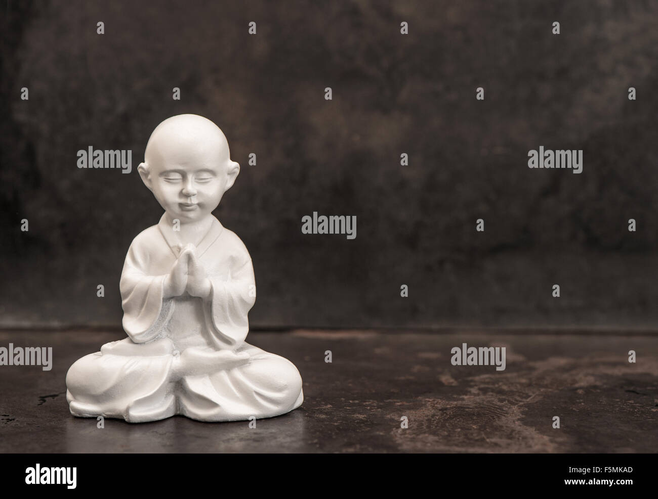 Praying buddha. White monk statue on dark background. Meditation ...