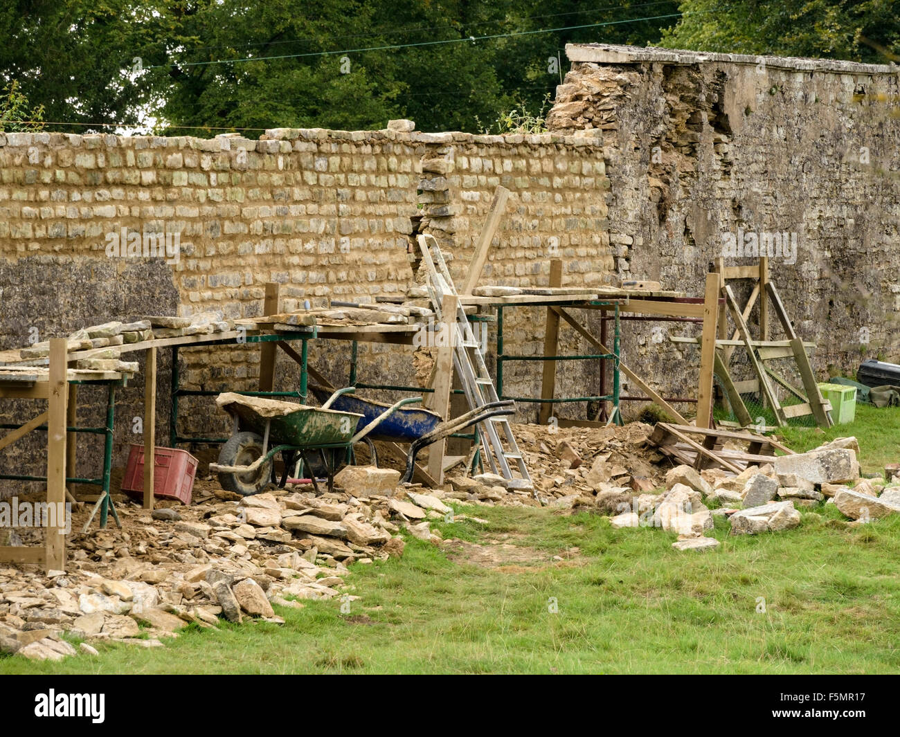 Old natural, limestone garden wall renovation and repair with builder's ...