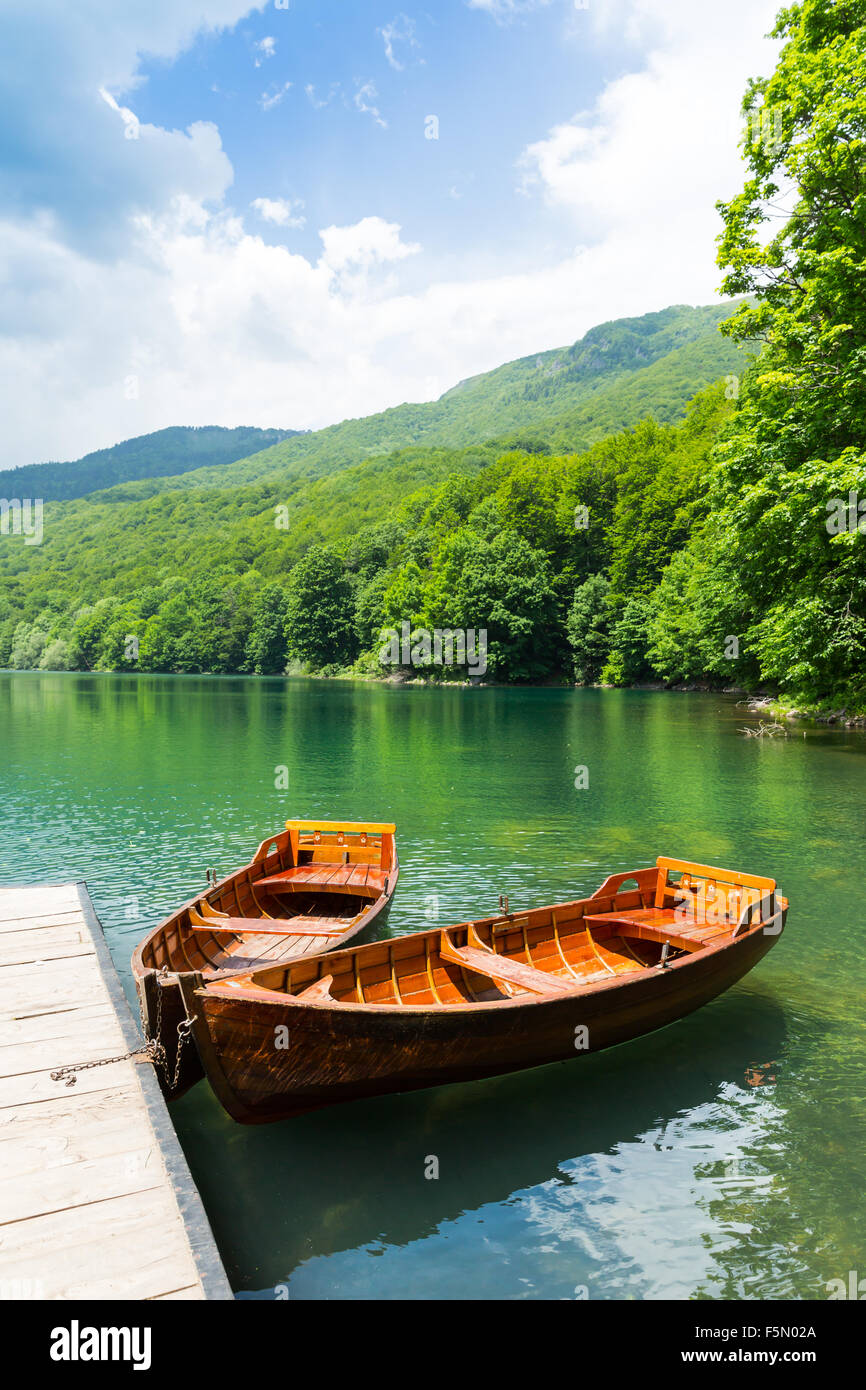Two wooden boats at pier on mountain lake. Biograd lake, Montenegro ...