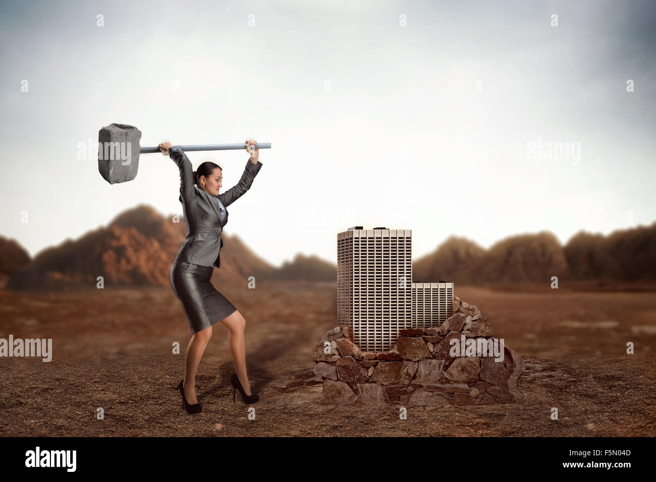 Businesswoman with sledgehammer tries to hammer a builging in the ...