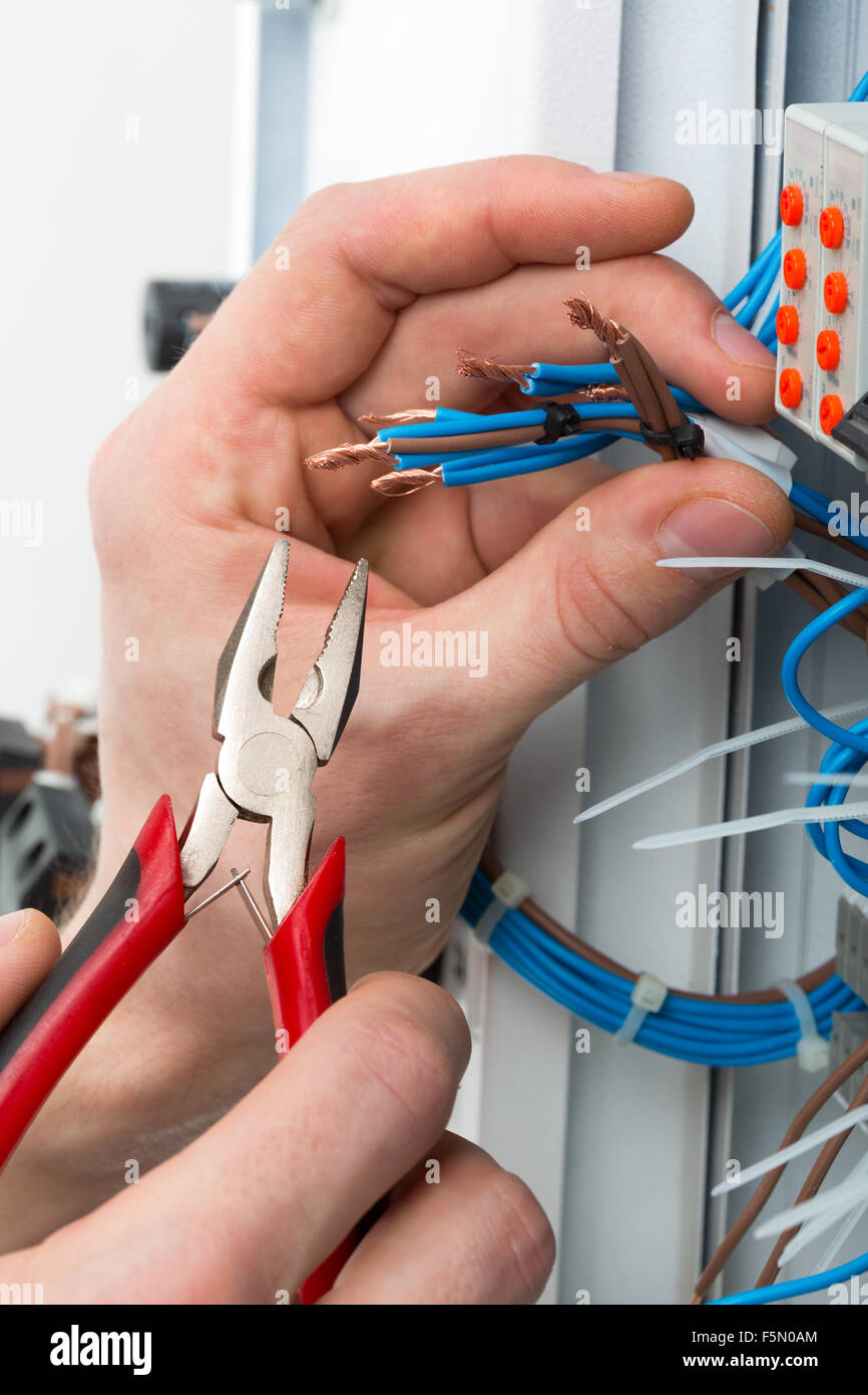 Hands of an electrician with tools at an electrical switchgear cabinet ...