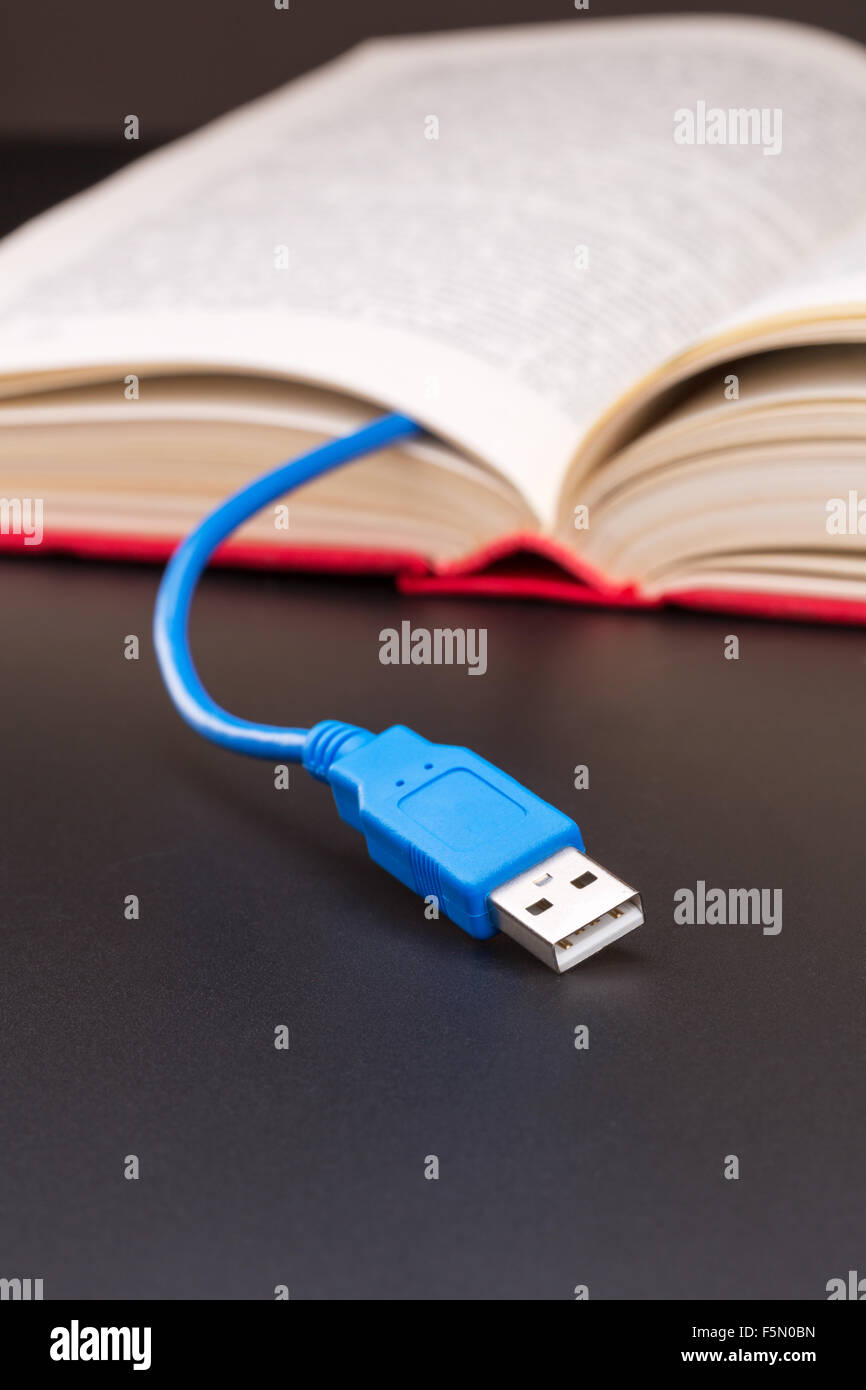 Blue usb cable sticks out from red book. Macro view Stock Photo - Alamy