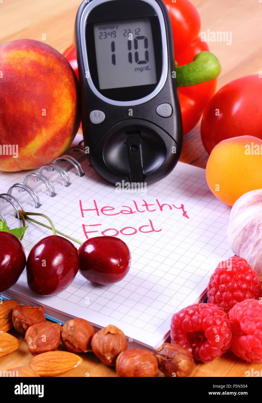 Fresh fruits, vegetables and glucose meter on notebook for writing ...