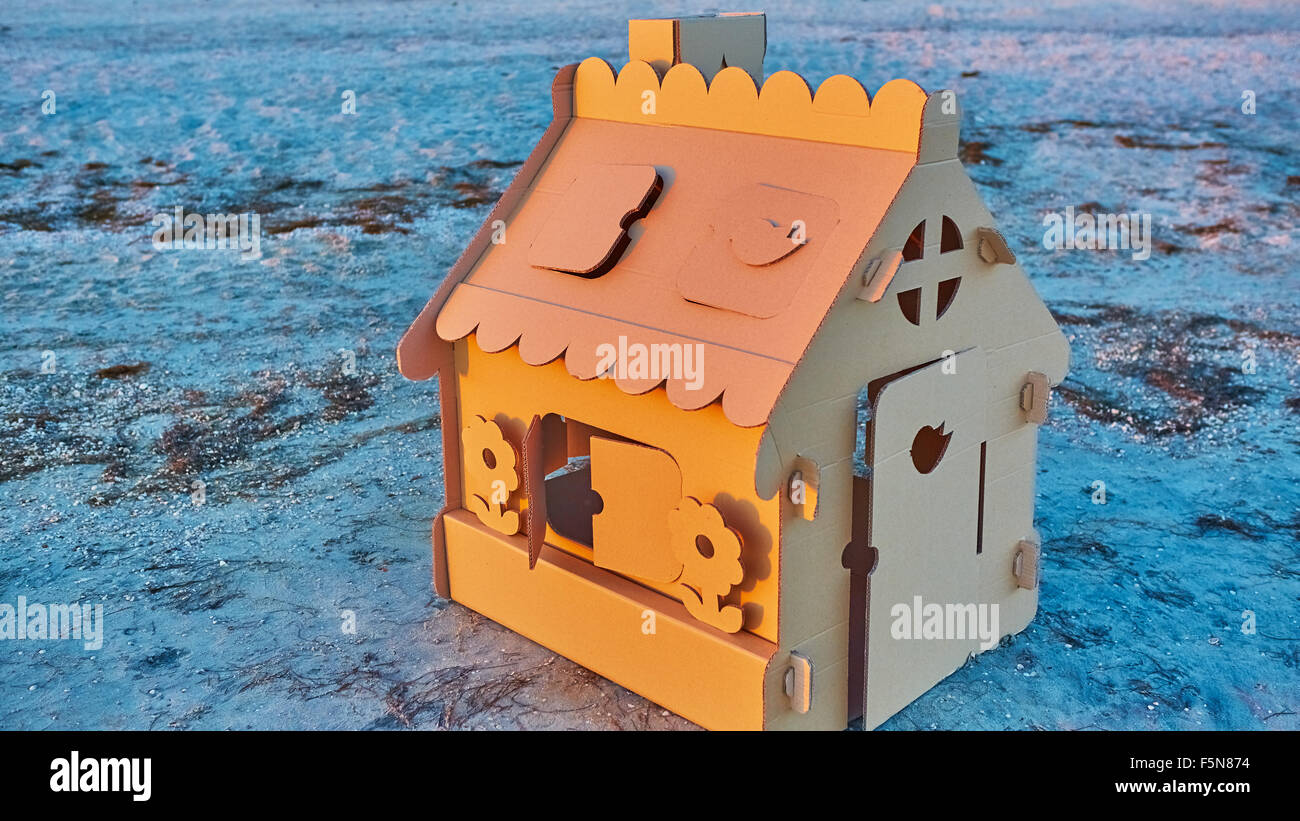 Toy house made of corrugated cardboard in the sea coast at sunset. The ...