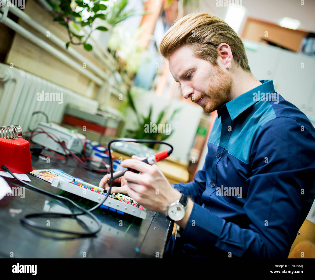 Young man working in electronics workshop Stock Photo - Alamy