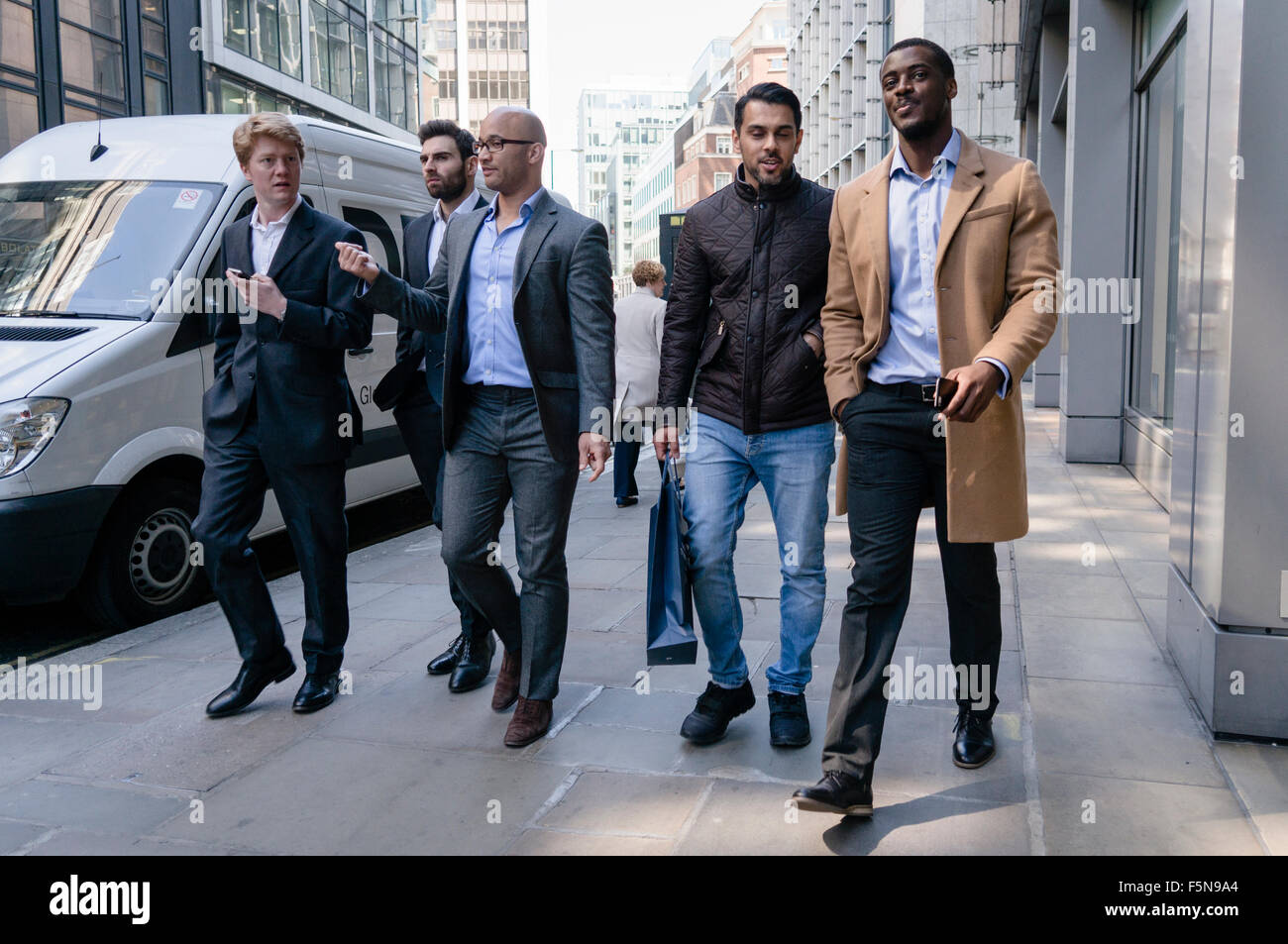 Young men walk down a street in the City of London Stock Photo - Alamy