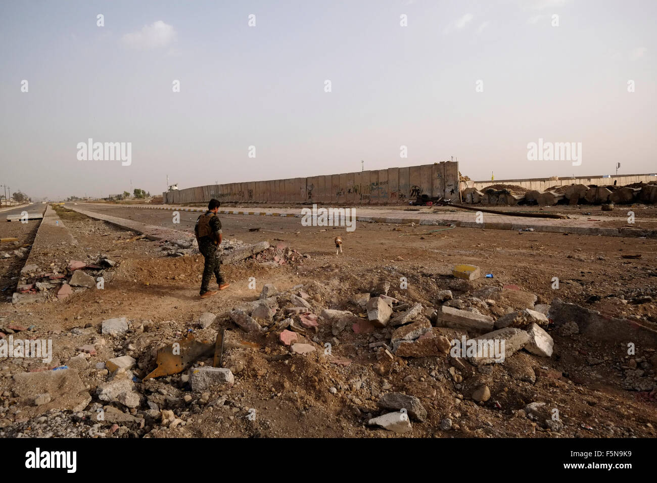 A Kurdish fighter walks through rubble caused by fierce fighting ...