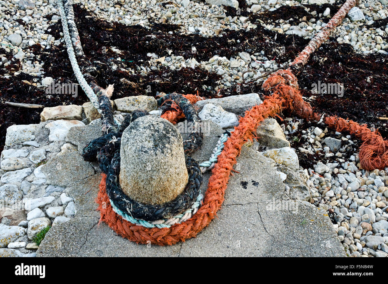 orange and white mooring ropes tethered around stone bollard Stock ...