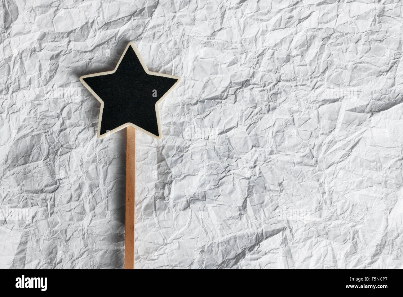 Wooden pointer in the shape of a star lying on a crumpled paper, as ...