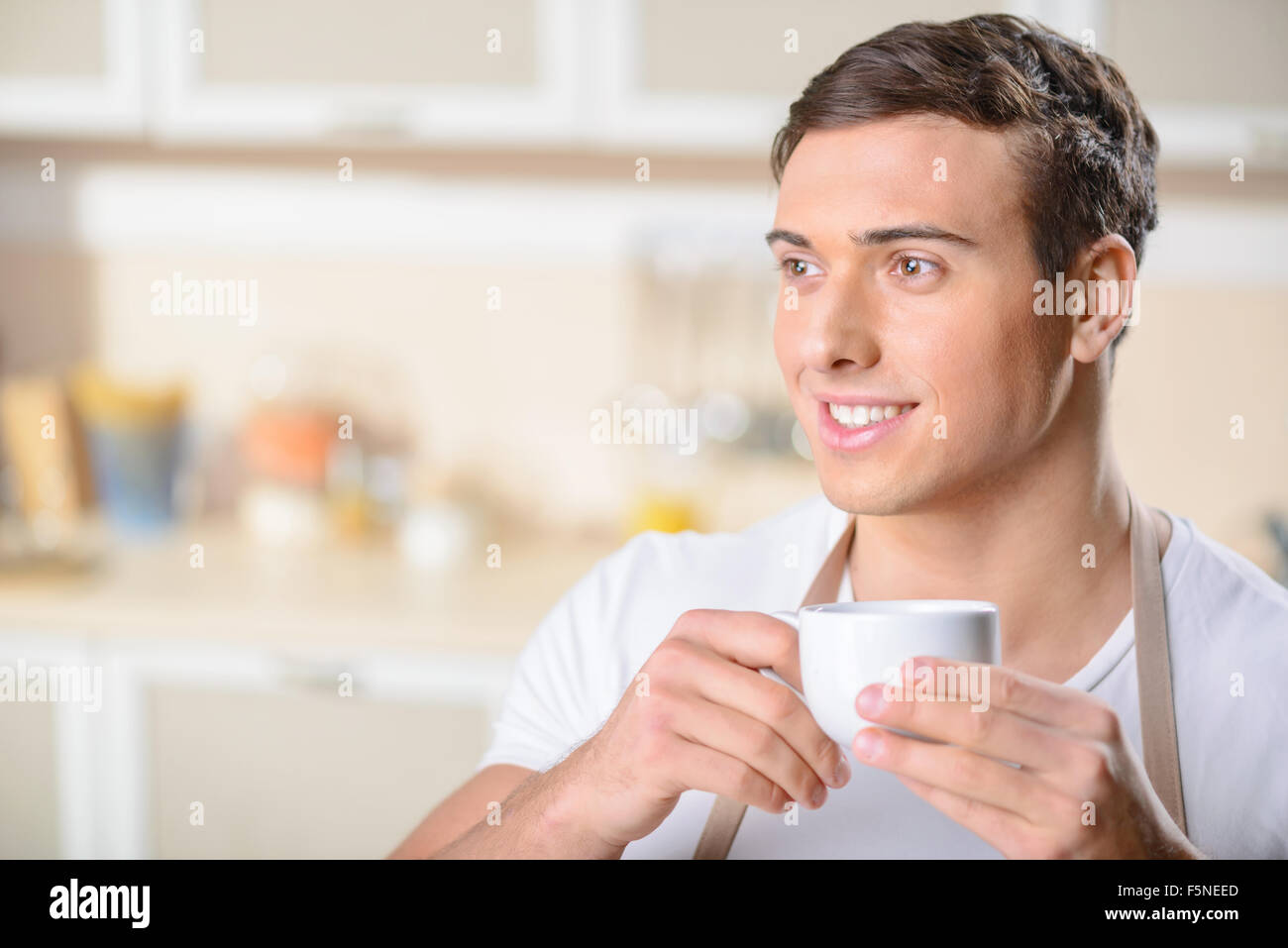 Smiling young man enjoys a cup pf coffee Stock Photo - Alamy
