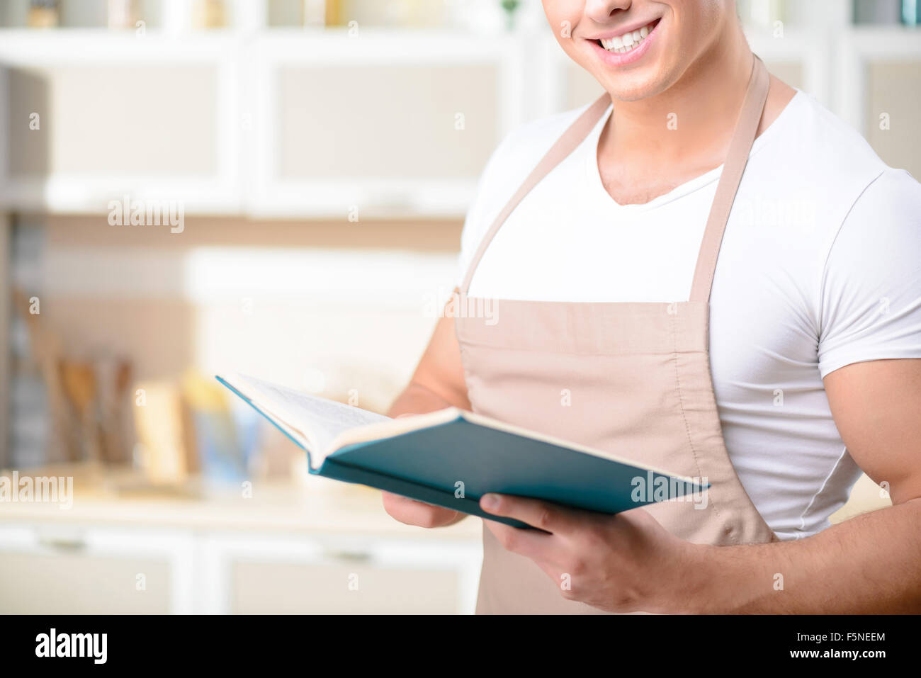 Young smiling cook is reading a cookbook Stock Photo - Alamy