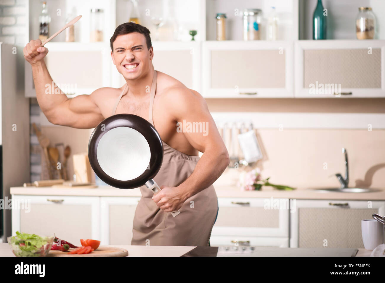 Cheerful young man posing with kitchen utensils Stock Photo - Alamy