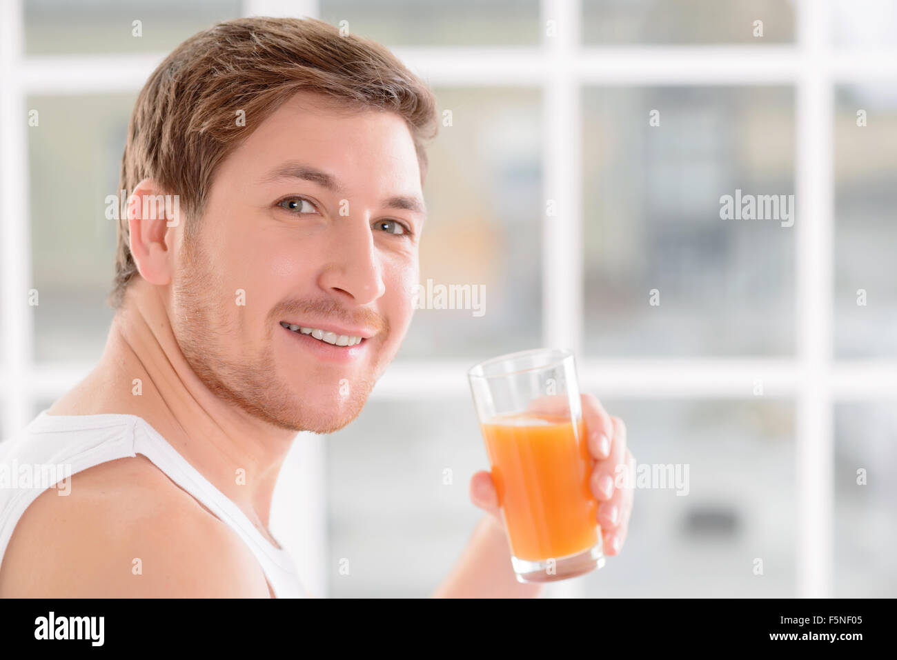 Young handsome guy enjoys a glass of juice Stock Photo - Alamy